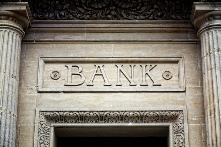 Old bank sign engraved in stone or concrete above the door of fi ...